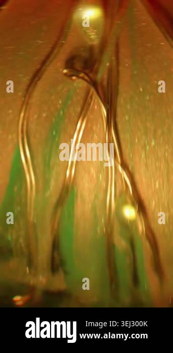 Vertical video. Golden ink drip. Light garland. Defocused yellow green ...