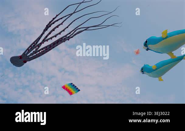 Colorful kite festival with giant inflatable kites flying in blue sky ...
