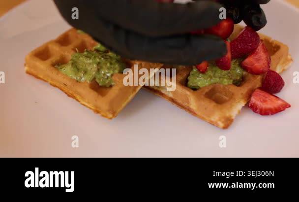 Garnishing waffles. Dessert serving. Unrecognizable chef hand in gloves ...