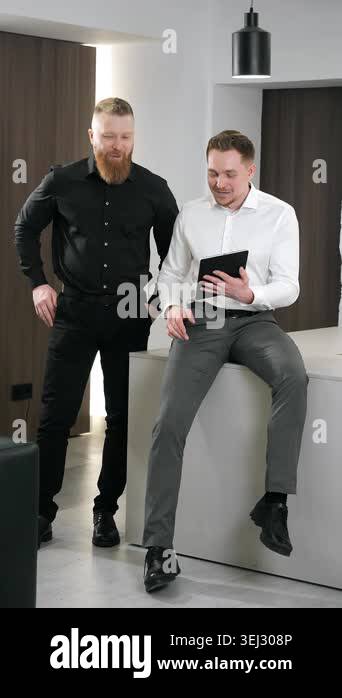 Two businessmen discussing project details using tablet in modern ...