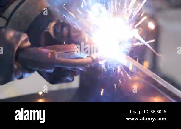 Close up of industrial welder using welding torch on metal with bright ...