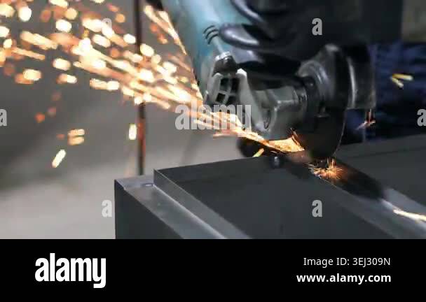 Close up of worker cutting metal with angle grinder in factory workshop ...