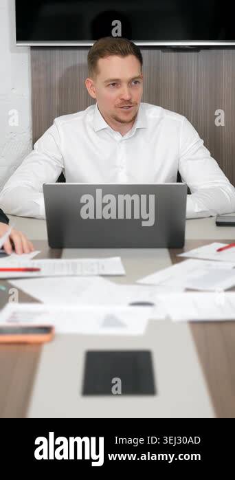 Young businessman speaking during office meeting with laptop and ...
