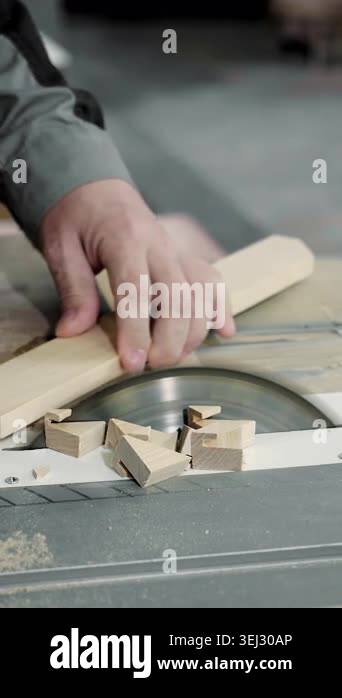 Worker cutting wooden pieces with circular saw in workshop, carpentry ...