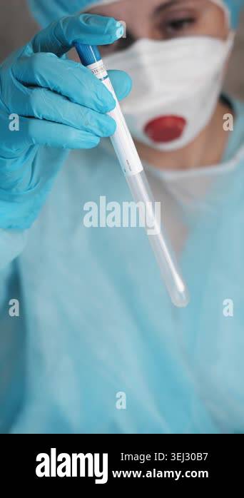 Scientist in protective equipment holding laboratory sample tube during ...