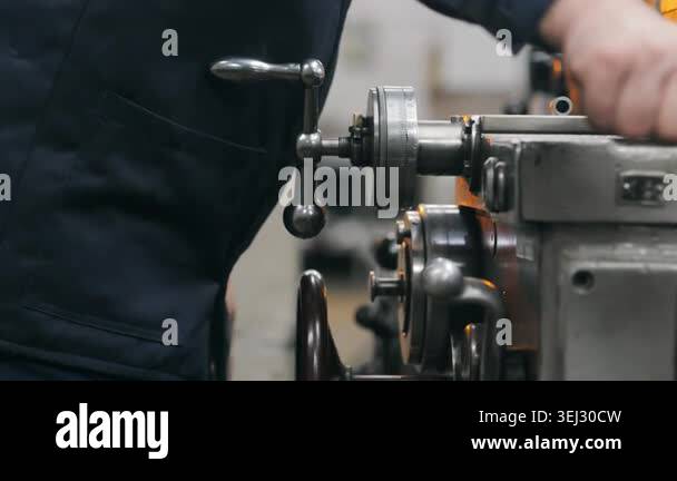 Close up of factory worker operating industrial lathe machine controls ...