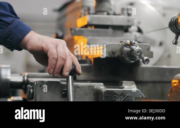 Close up of factory worker hand operating industrial lathe machine ...