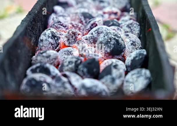 Side view of glowing hot charcoal in metal brazier for home barbecue ...