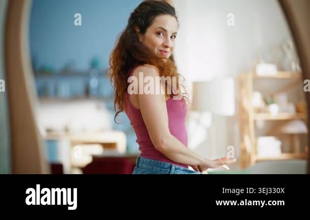 Fit girl looking reflection wearing large jeans in home bedroom closeup ...