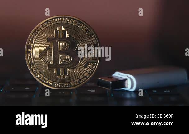 Bitcoin cryptocurrency coin on laptop keyboard with warm neon lighting ...