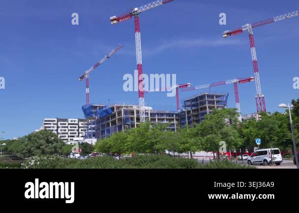 Multiple red and white tower cranes operating on a construction area ...
