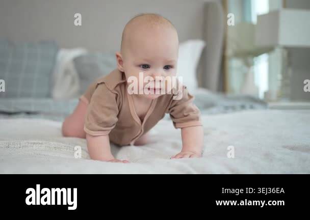 Happy baby. Cute little newborn girl with smiling face sitting on bed ...