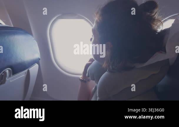 Passenger woman is flying in plane. Girl sitting in airplane looking ...