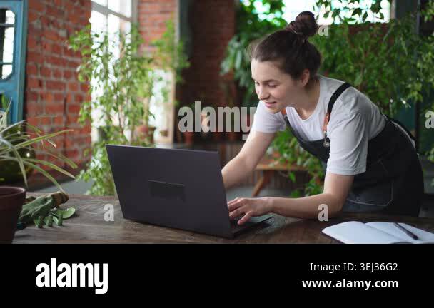 Female florist gardener working in botanical store greenhouse using ...