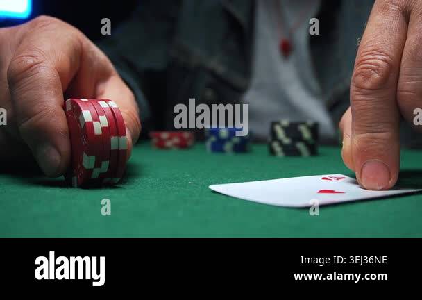 Player places a red poker chips on a green felt table, pointing at a ...