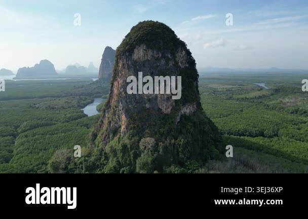 Aerial footage circling a monumental limestone karst mountain rising ...