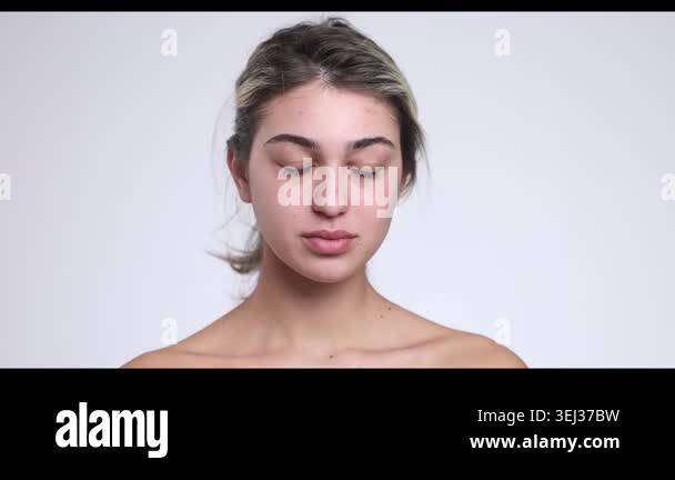4K video portrait of young woman with tied hair looking aside then ...