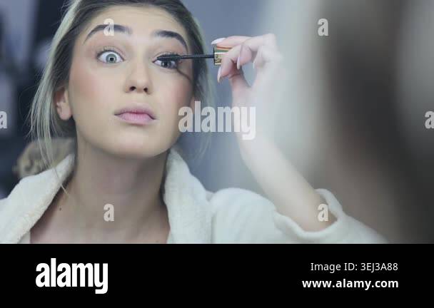 4K slow motion video of young woman applying mascara to eyelashes while ...