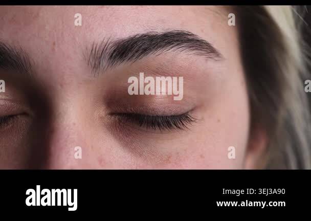 4K video closeup of young woman opening eye and raising eyebrow, subtle ...