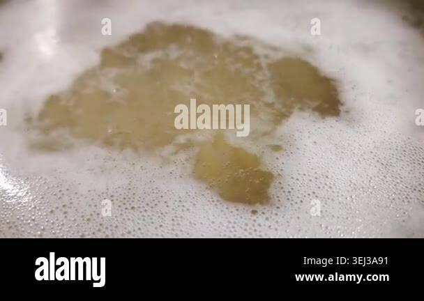 Boiling pasta in a pot with bubbling water and foam, showing gradual ...