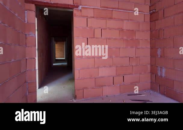 Unfinished room interior of house under construction. Brick red walls ...