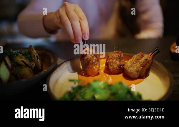 Close up of a woman's hand dipping grilled food into a rich sauce Stock ...