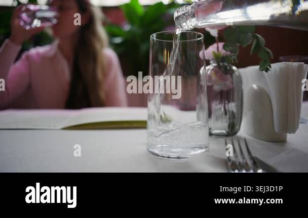 Close up of water being poured from a glass bottle into a clear ...