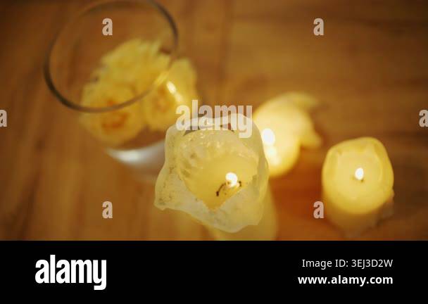 Close up of melted ivory wax candles burning on a wooden table, with ...