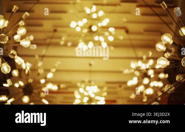 Upward view of modern decorative chandeliers with multiple glowing ...