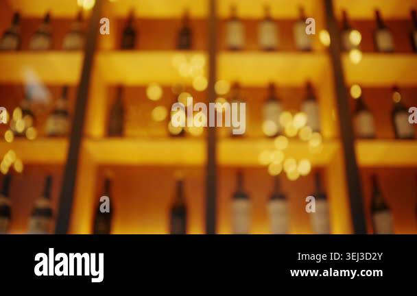 Artistic blurred shot of wine bottles displayed on illuminated shelves ...