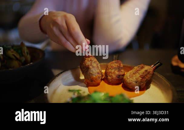 Close up of a woman's hand dipping grilled food into a rich sauce Stock ...