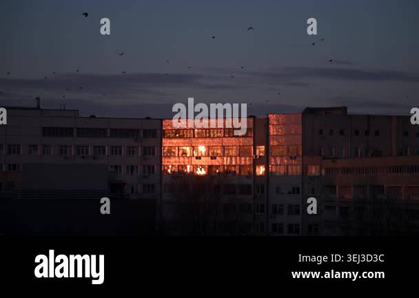 Cinematic shot of city buildings reflecting warm sunset light while ...