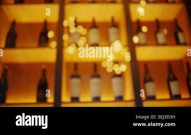 Artistic blurred shot of wine bottles displayed on illuminated shelves ...