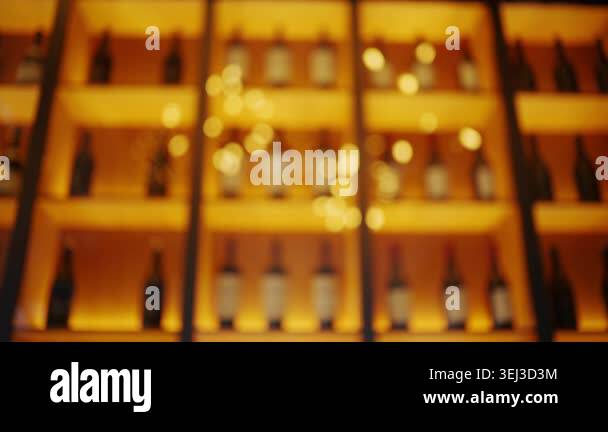 Artistic blurred shot of wine bottles displayed on illuminated shelves ...