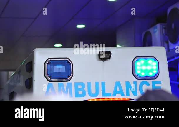 An ambulance at an emergency entrance at night with flashing blue ...