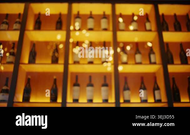 Artistic blurred shot of wine bottles displayed on illuminated shelves ...