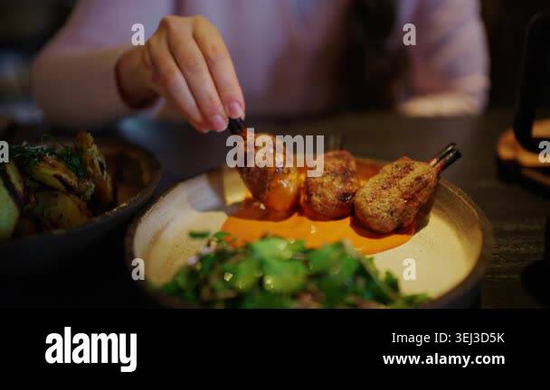 Close up of a woman's hand dipping grilled food into a rich sauce Stock ...