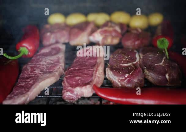 Meat cooking on a grill with eggplant and red peppers, with smoke ...