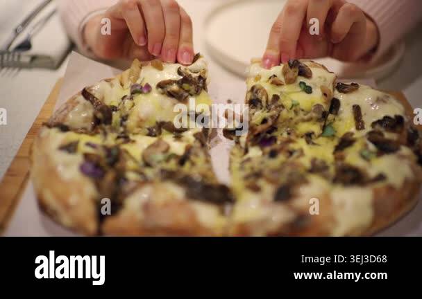 Close up of a woman pulling apart slices of a freshly baked mushroom ...