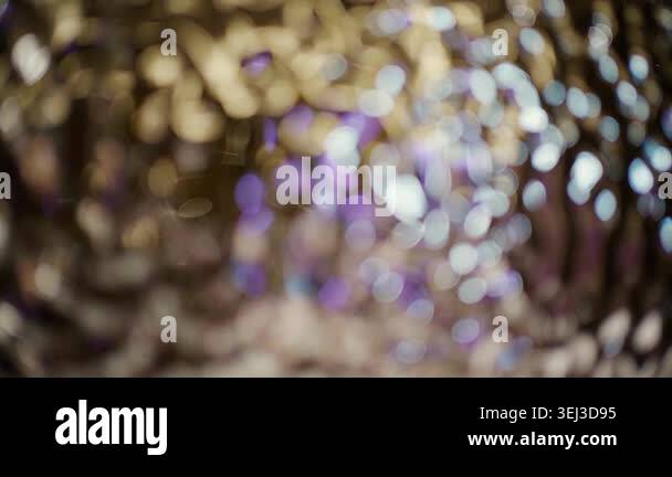 Abstract close up of golden, white, and purple bokeh lights with a soft ...
