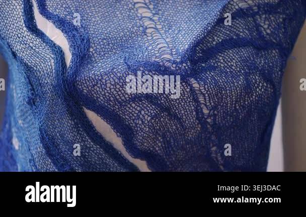 Close up of a blue openwork knitted textile stretched over a white form ...