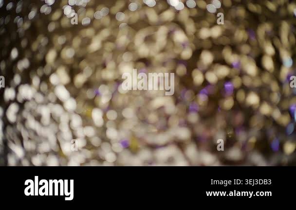 Abstract close up of golden, white, and purple bokeh lights with a soft ...