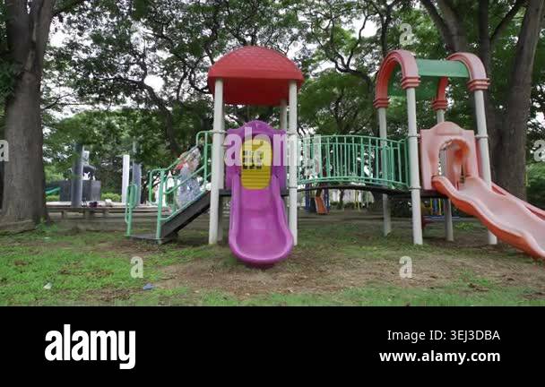 Cute young Asian girl having fun sliding down a purple slide at the ...