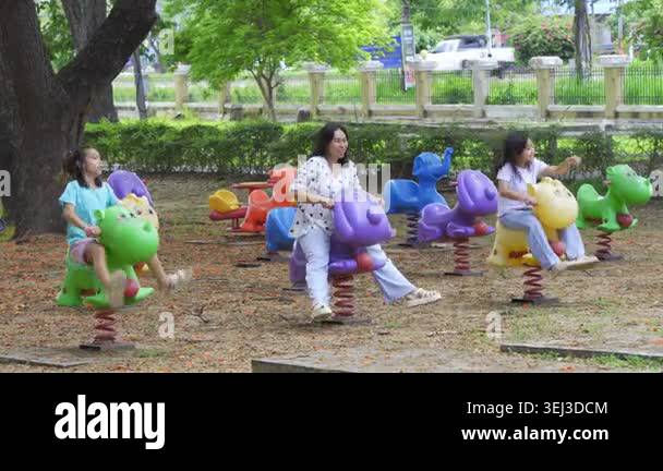 Happy Asian mother and her two daughters riding colorful spring riders ...