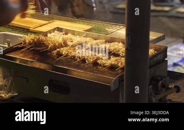 Close-up of bacon wrapped enoki mushroom skewers cooking on a flat top ...