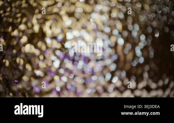 Abstract close up of golden, white, and purple bokeh lights with a soft ...