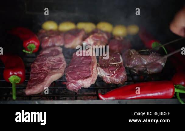 Meat cooking on a grill with eggplant and red peppers, with smoke ...