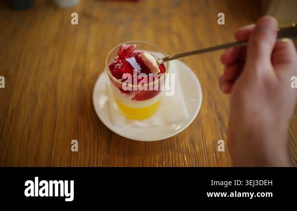 Close up of a spoon lifting a piece of bright red fruit jelly from a ...