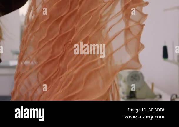 Close up of translucent orange organza fabric with raised wavy stitched ...