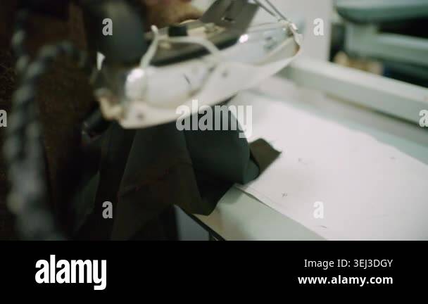 Close up of a tailor using a professional steam iron on black fabric in ...